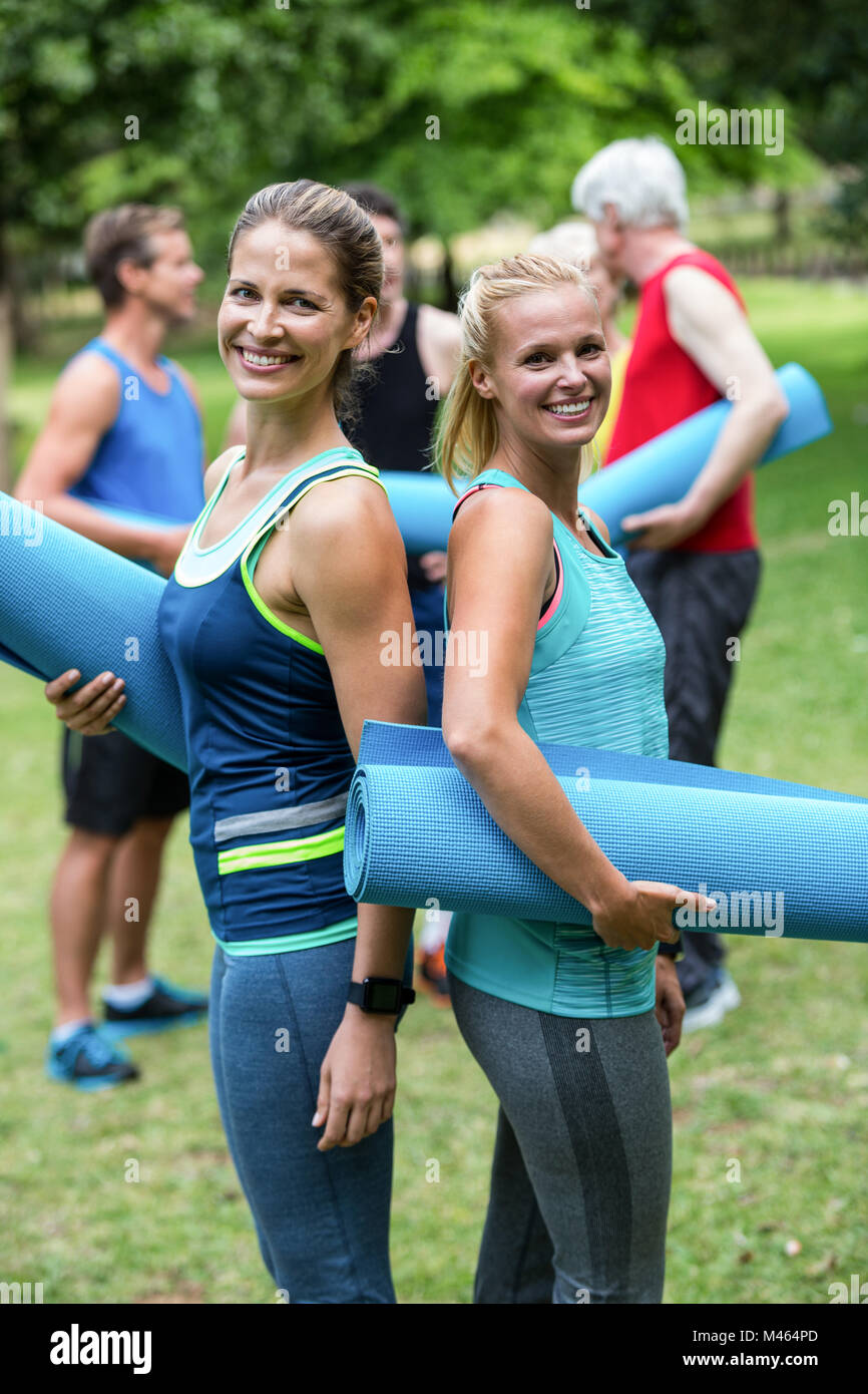 Fit women posing with sports mats back to back Stock Photo - Alamy