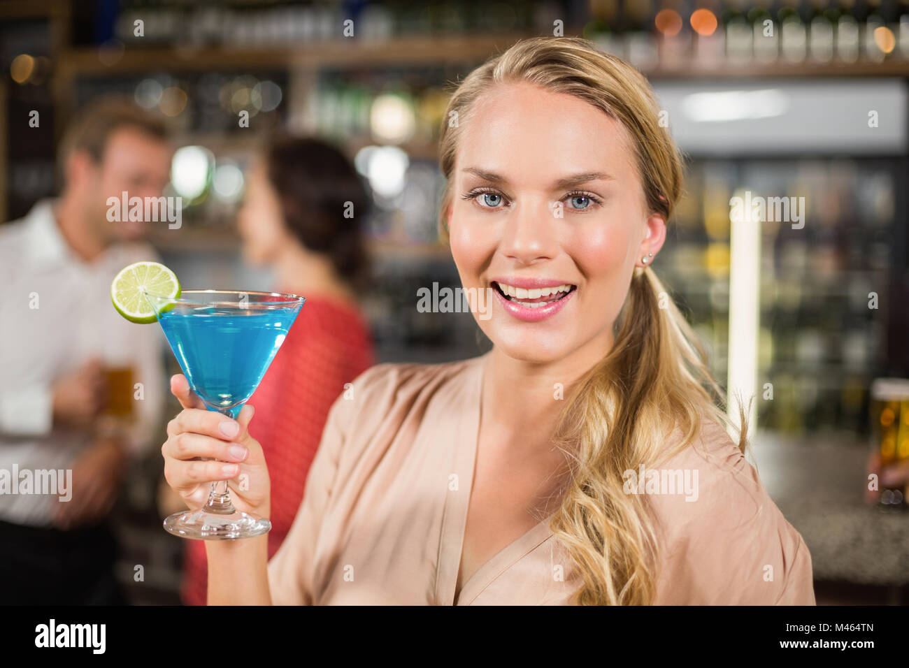 Attractive woman holding cocktail glass facing camera Stock Photo - Alamy