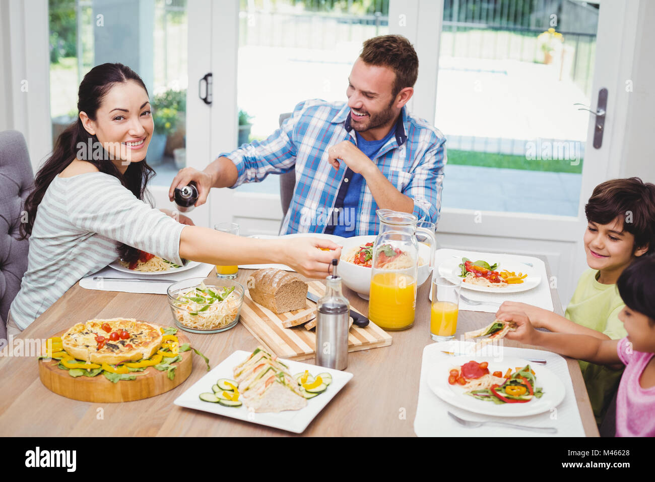 Happy family having food while sitting at dining table Stock Photo - Alamy