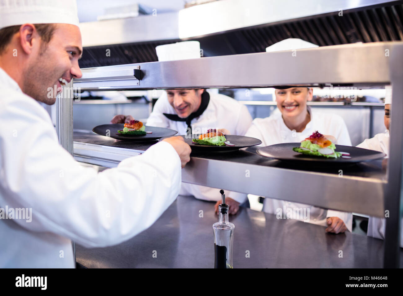 Chef handing appetizer plate through order station Stock Photo - Alamy