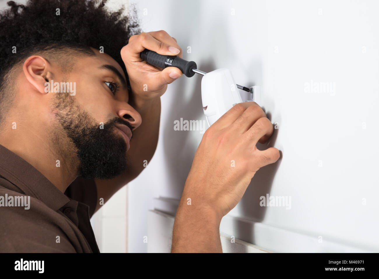 Side View Of A Male Technician Installing Security System Motion Sensor ...
