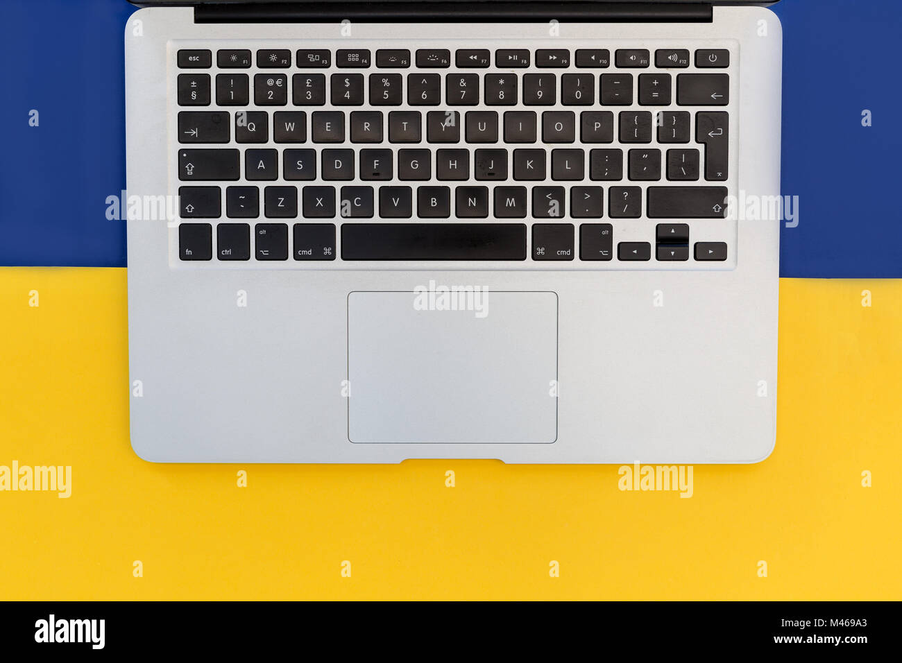 Laptop computer keyboard overhead on minimal bright yellow and blue ...