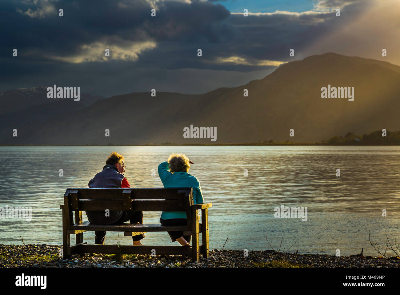 A couple enjoying a waterside seat at sunset Stock Photo - Alamy