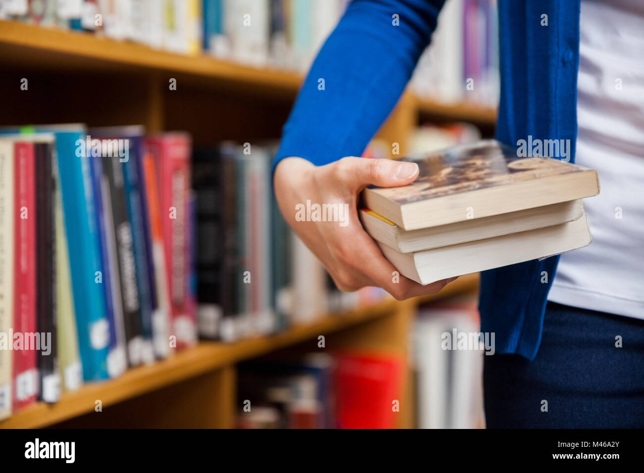 Happy female student taking books in the library Stock Photo - Alamy