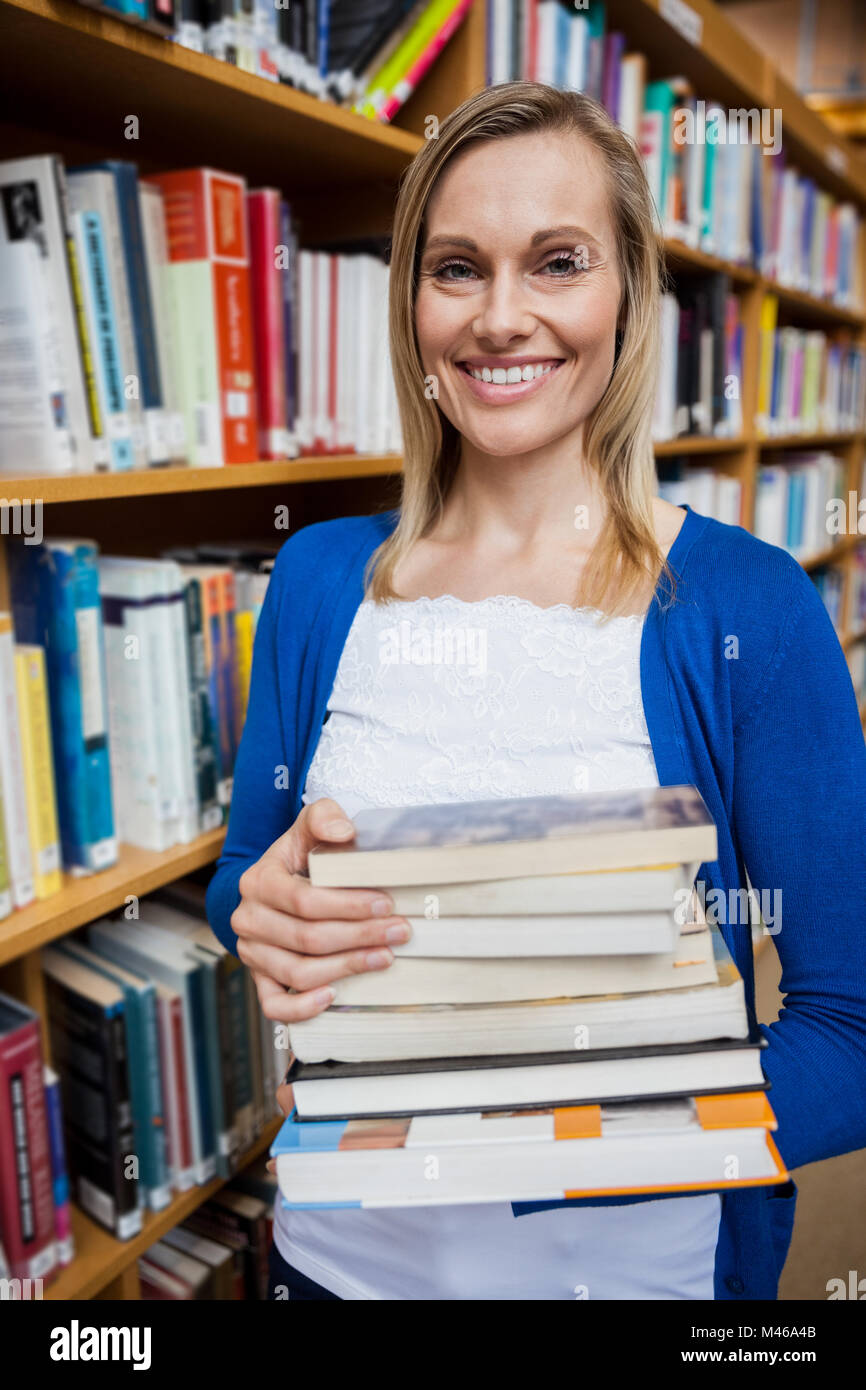 Happy female student taking books in the library Stock Photo - Alamy