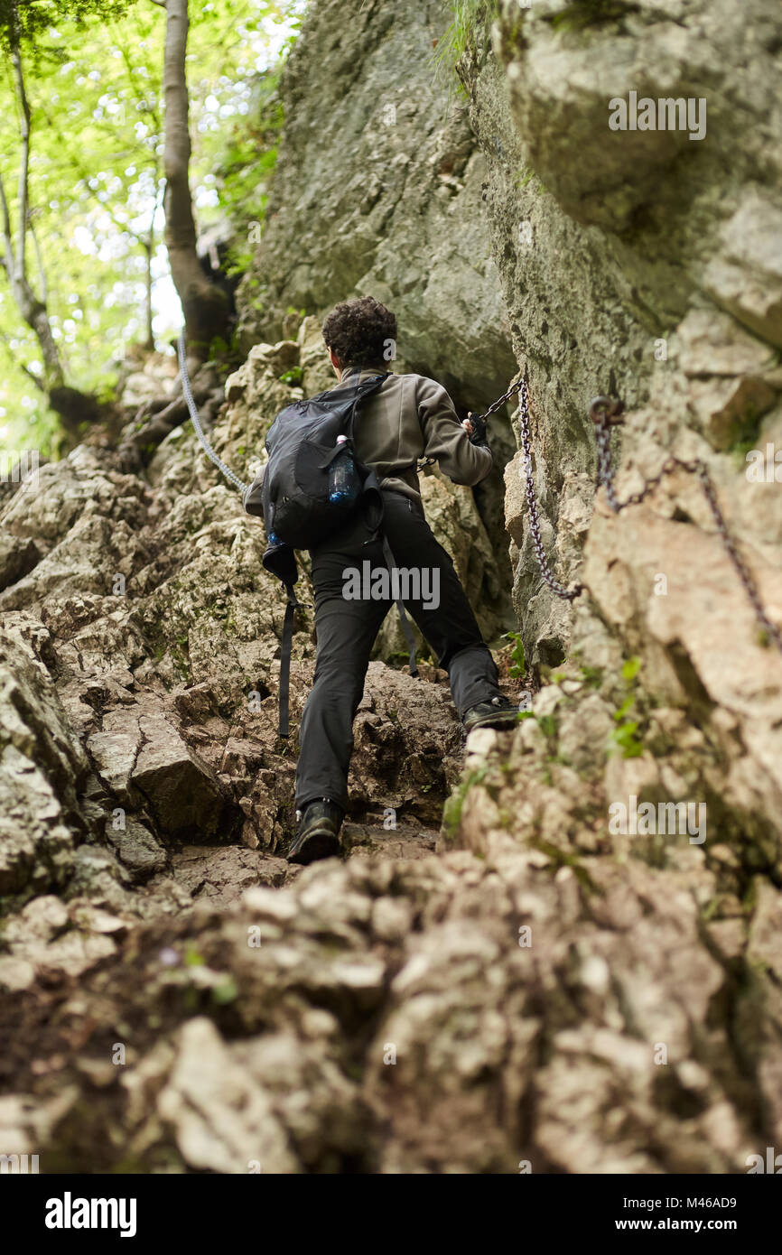 Young man climbing on mountain wall using safety chains Stock Photo - Alamy
