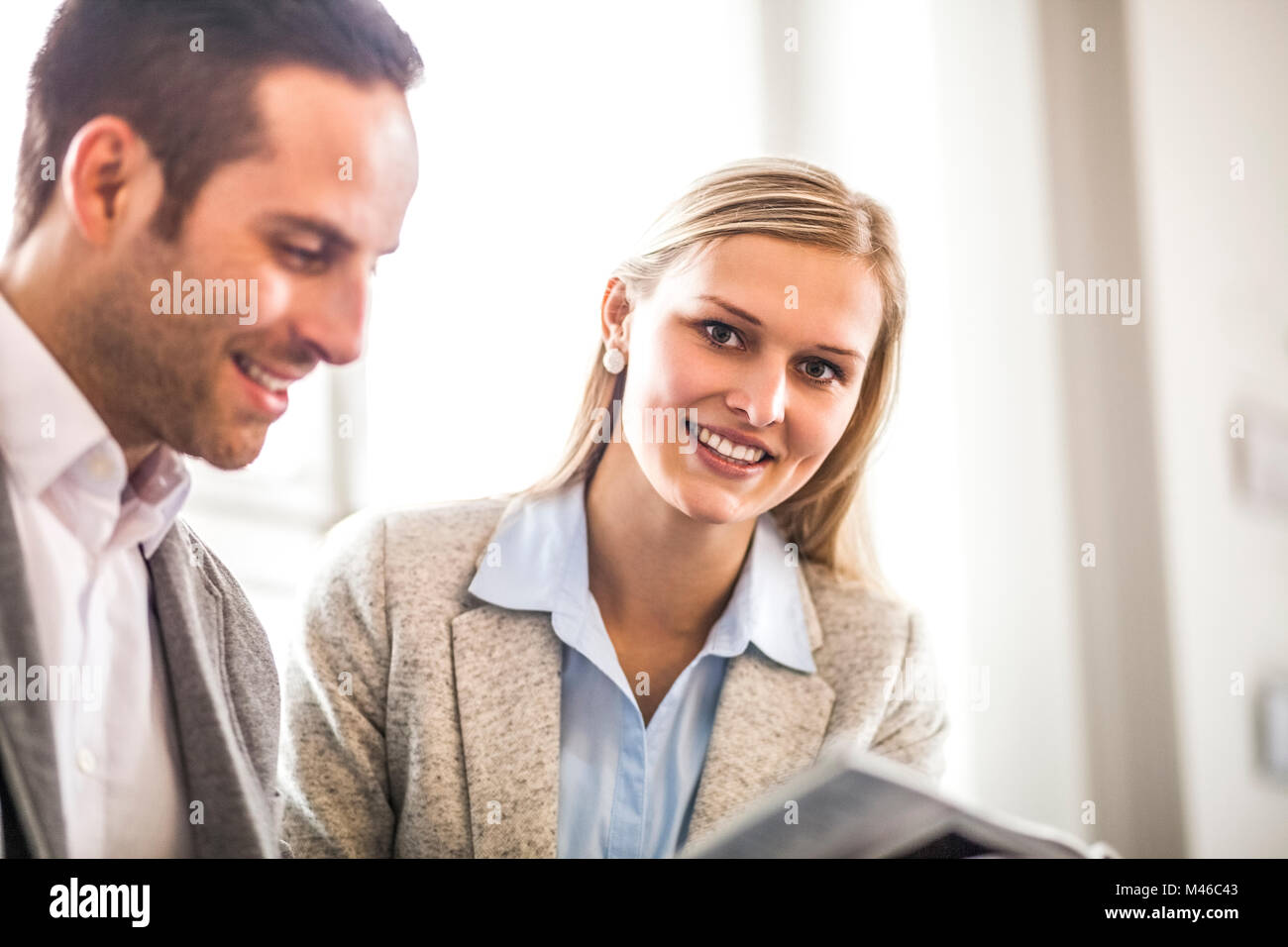 Portrait of beautiful young businesswoman with male colleague in office ...