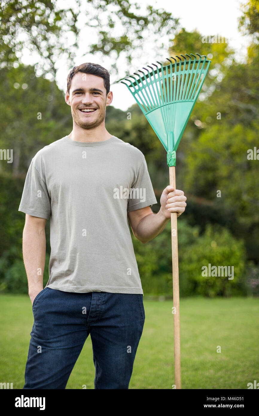 Portrait of young man standing with a gardening rake Stock Photo - Alamy