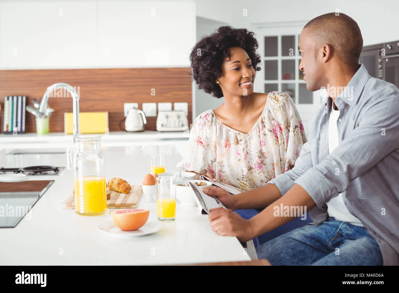 Smiling couple eating breakfast together in the kitchen Stock Photo - Alamy