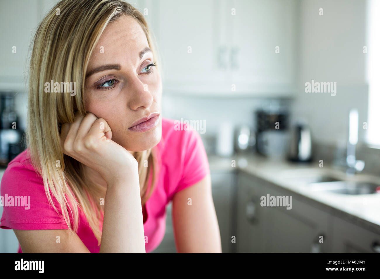 Thoughtful blonde woman leaning on her counter Stock Photo - Alamy