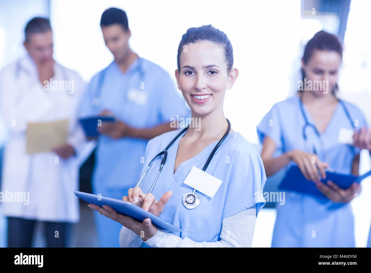 Female doctor using tablet and smiling at camera Stock Photo - Alamy