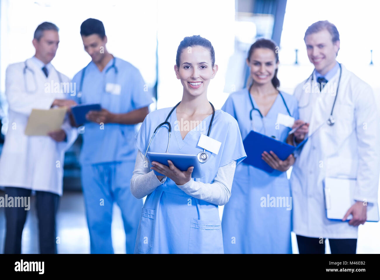 Female doctor using tablet and smiling at camera Stock Photo - Alamy