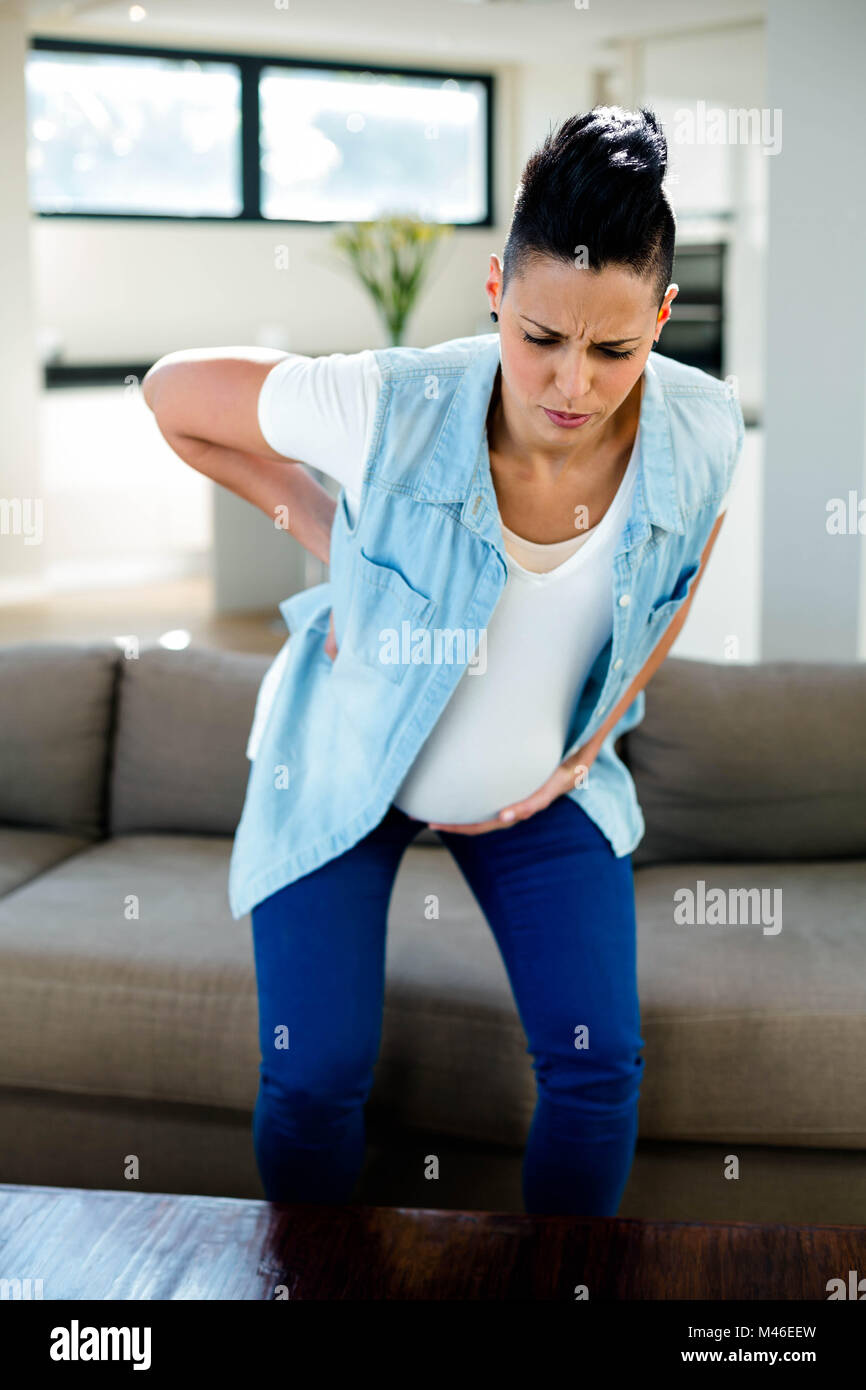 Pregnant woman bending forward with hand on hip Stock Photo - Alamy