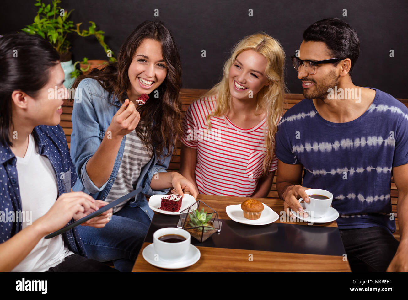Smiling friends enjoying coffee together and using technologies Stock ...