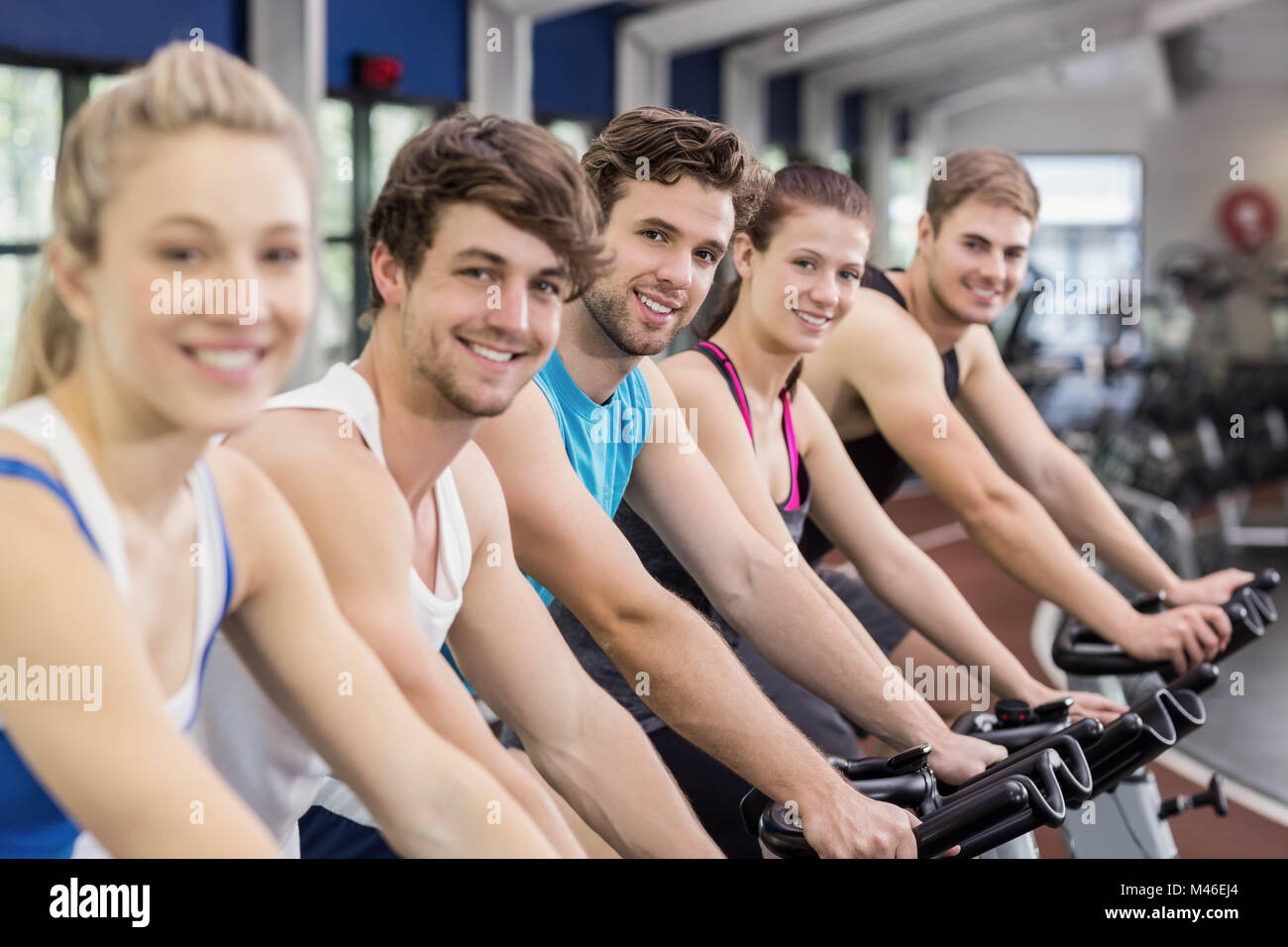 Fit group of people using exercise bike together Stock Photo - Alamy