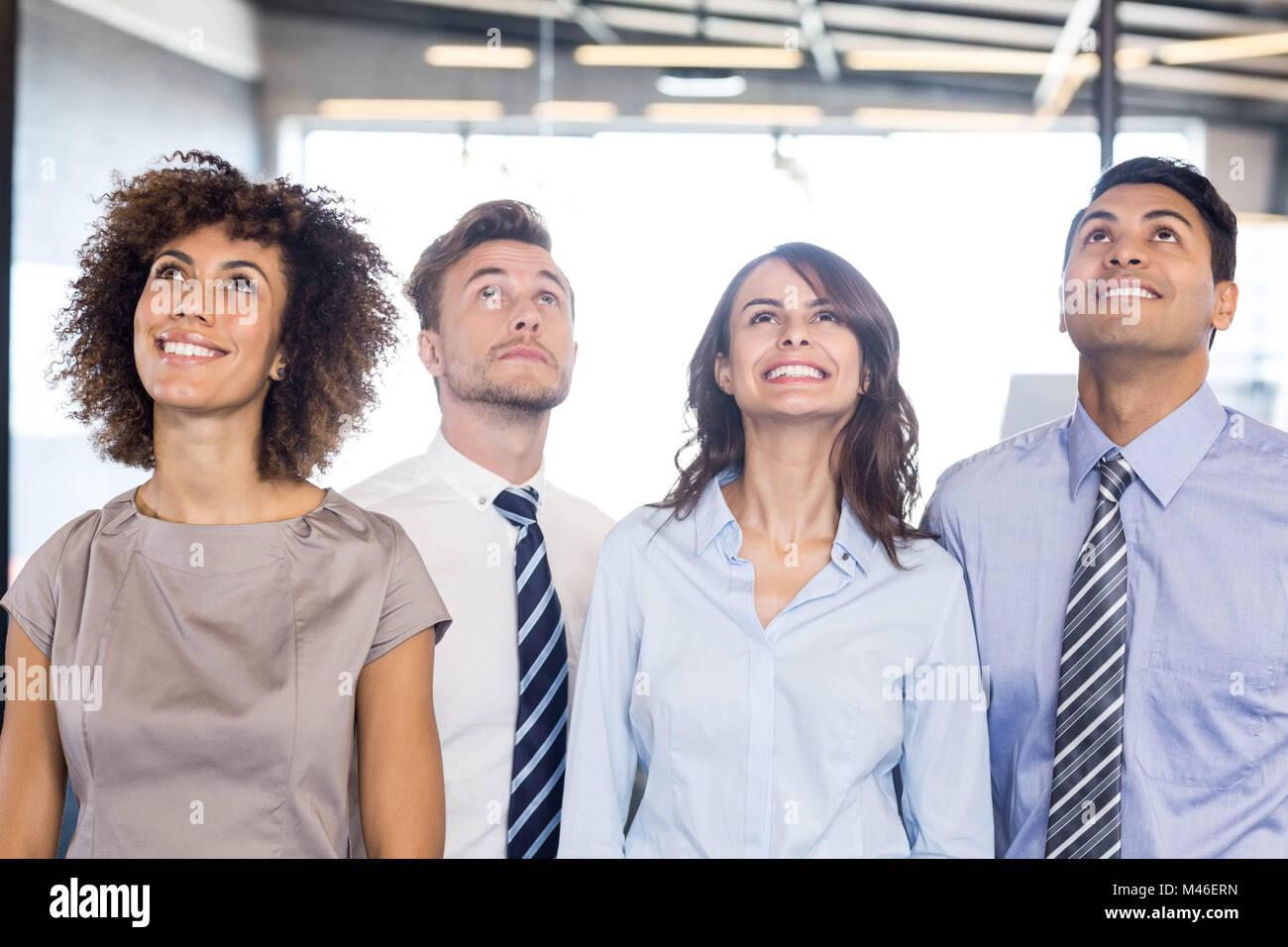 Portrait of business team looking up in office Stock Photo - Alamy