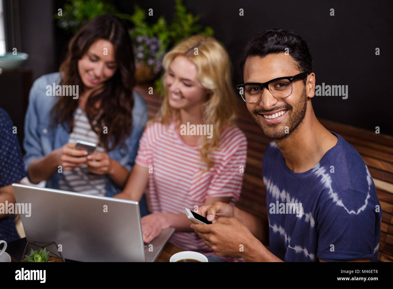 Smiling friends enjoying coffee together and using technologies Stock ...