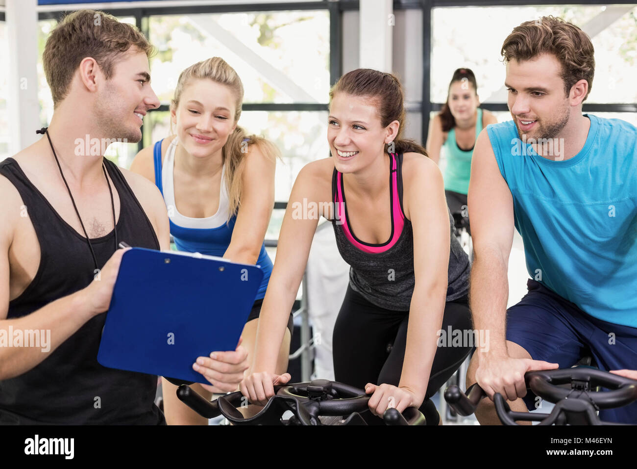 Fit group of people using exercise bike together Stock Photo - Alamy