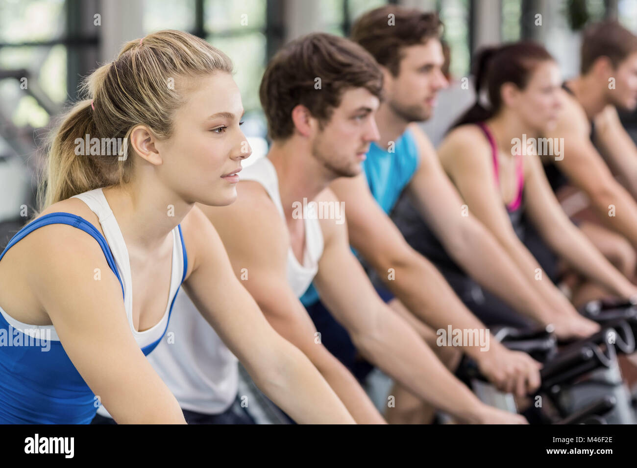 Fit group of people using exercise bike together Stock Photo - Alamy