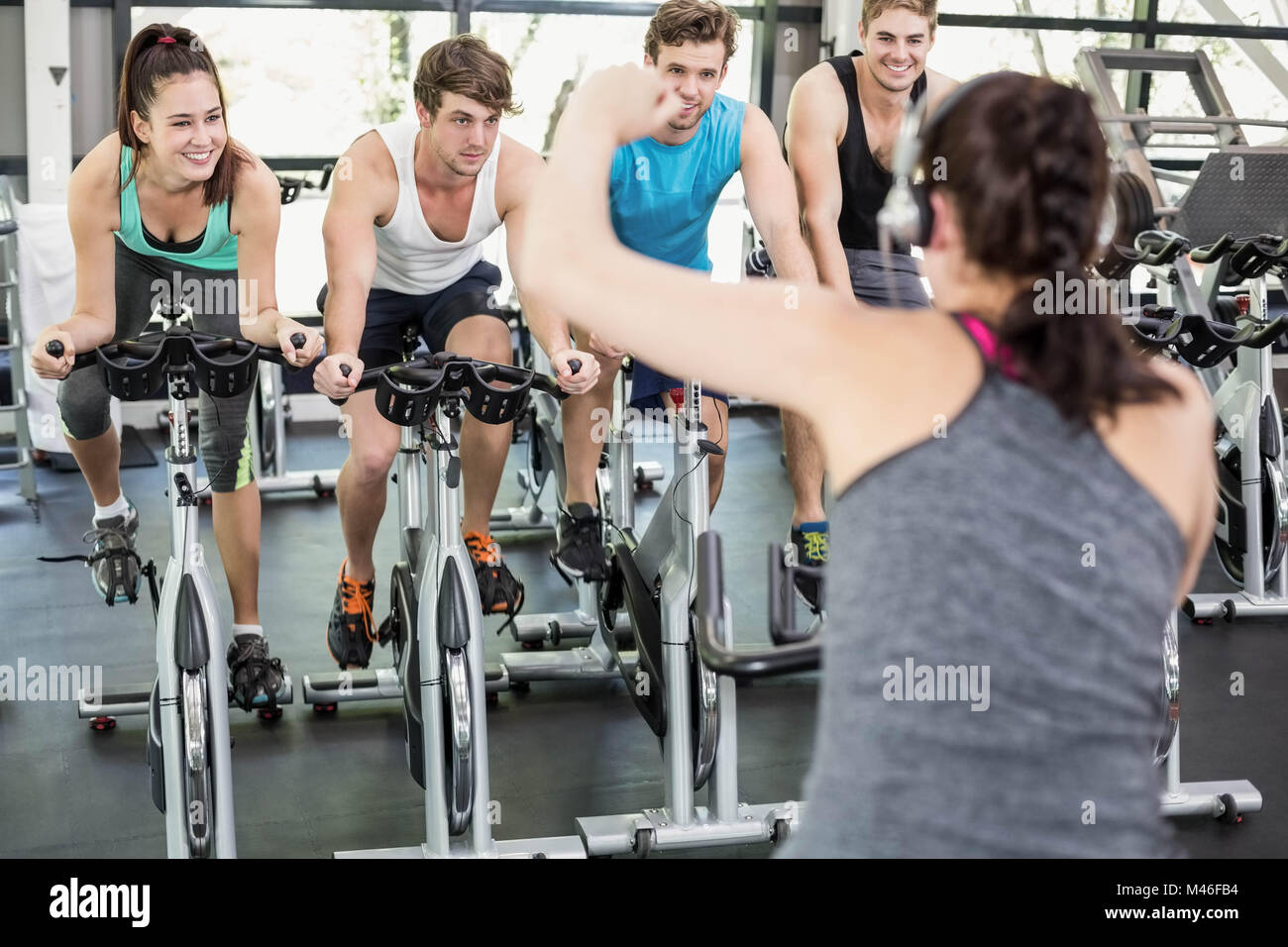 Fit group of people using exercise bike together Stock Photo - Alamy