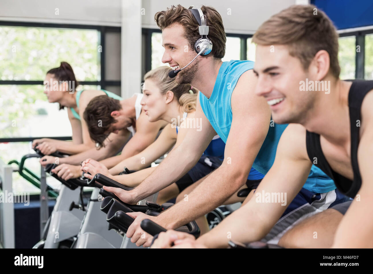 Fit group of people using exercise bike together Stock Photo - Alamy