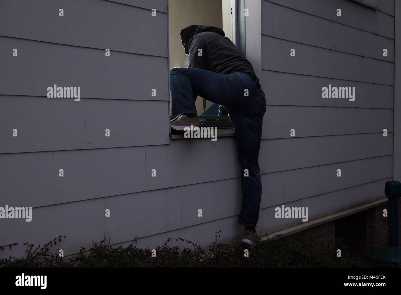 Rear View Of A Burglar Entering In A House Through A Window Stock Photo ...