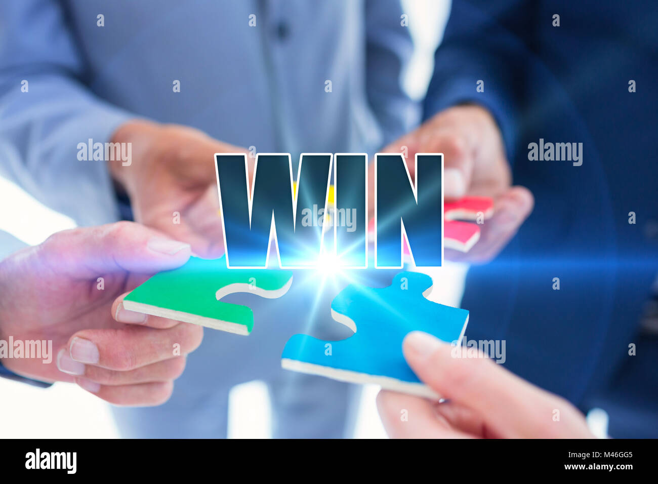 Win against business colleagues holding piece of puzzle Stock Photo - Alamy
