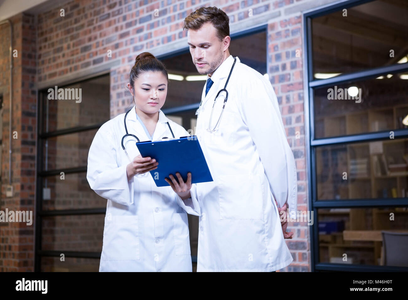 Two doctors looking at clipboard and discussing near library Stock ...