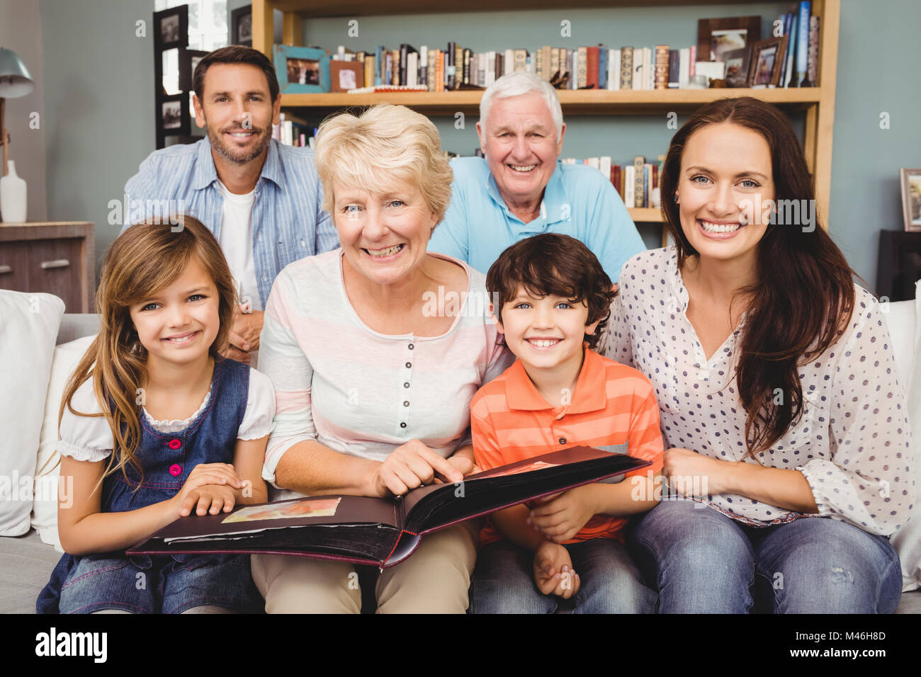 Portrait of smiling family with grandparents holding photo album Stock ...