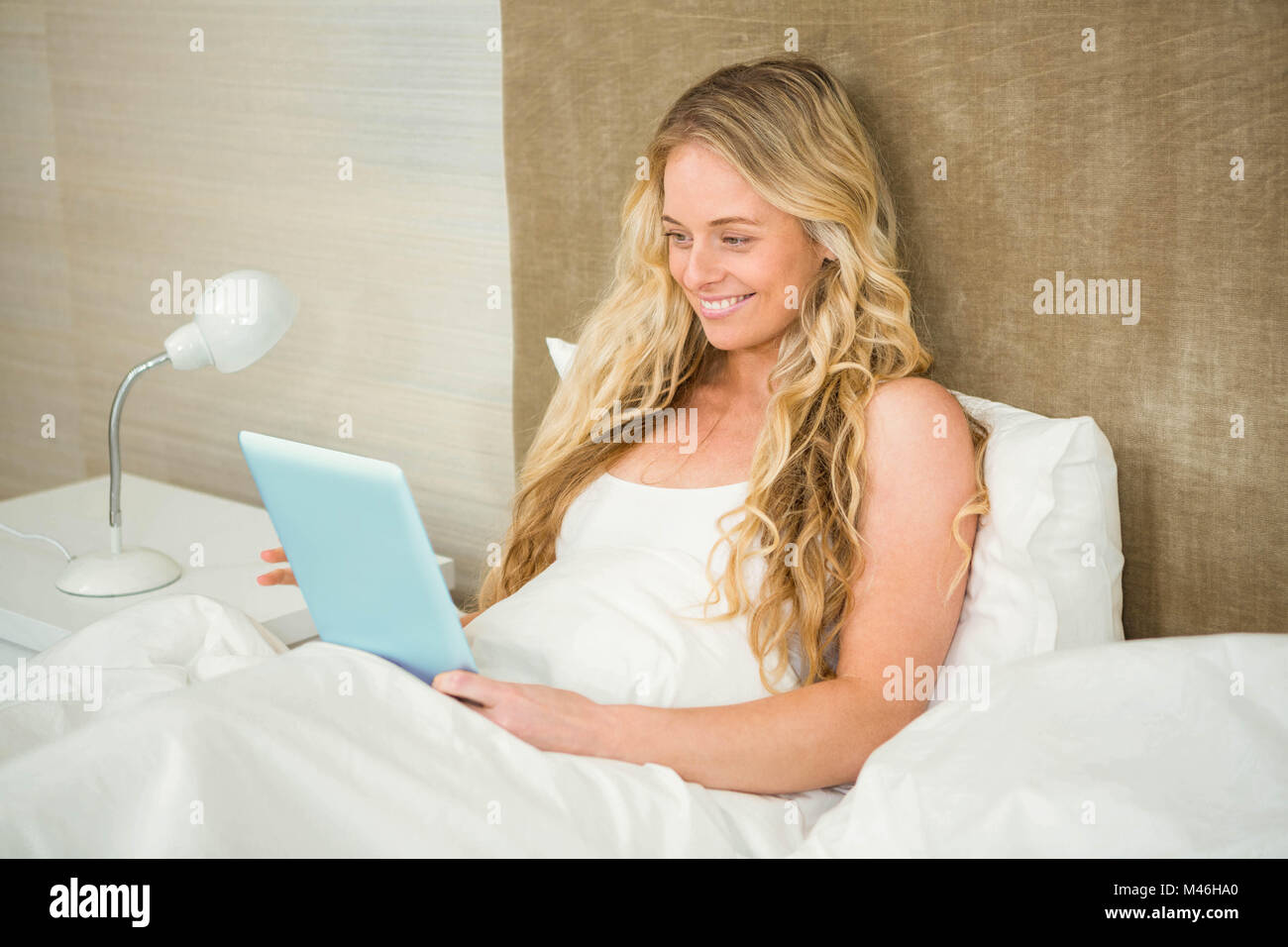 Pretty woman using tablet computer in her bed Stock Photo - Alamy