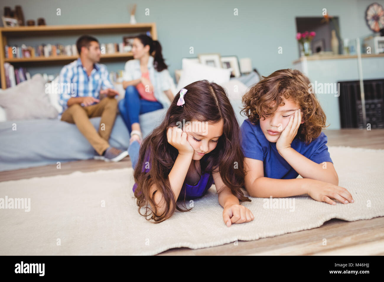 Children resting on carpet while parents in background Stock Photo - Alamy