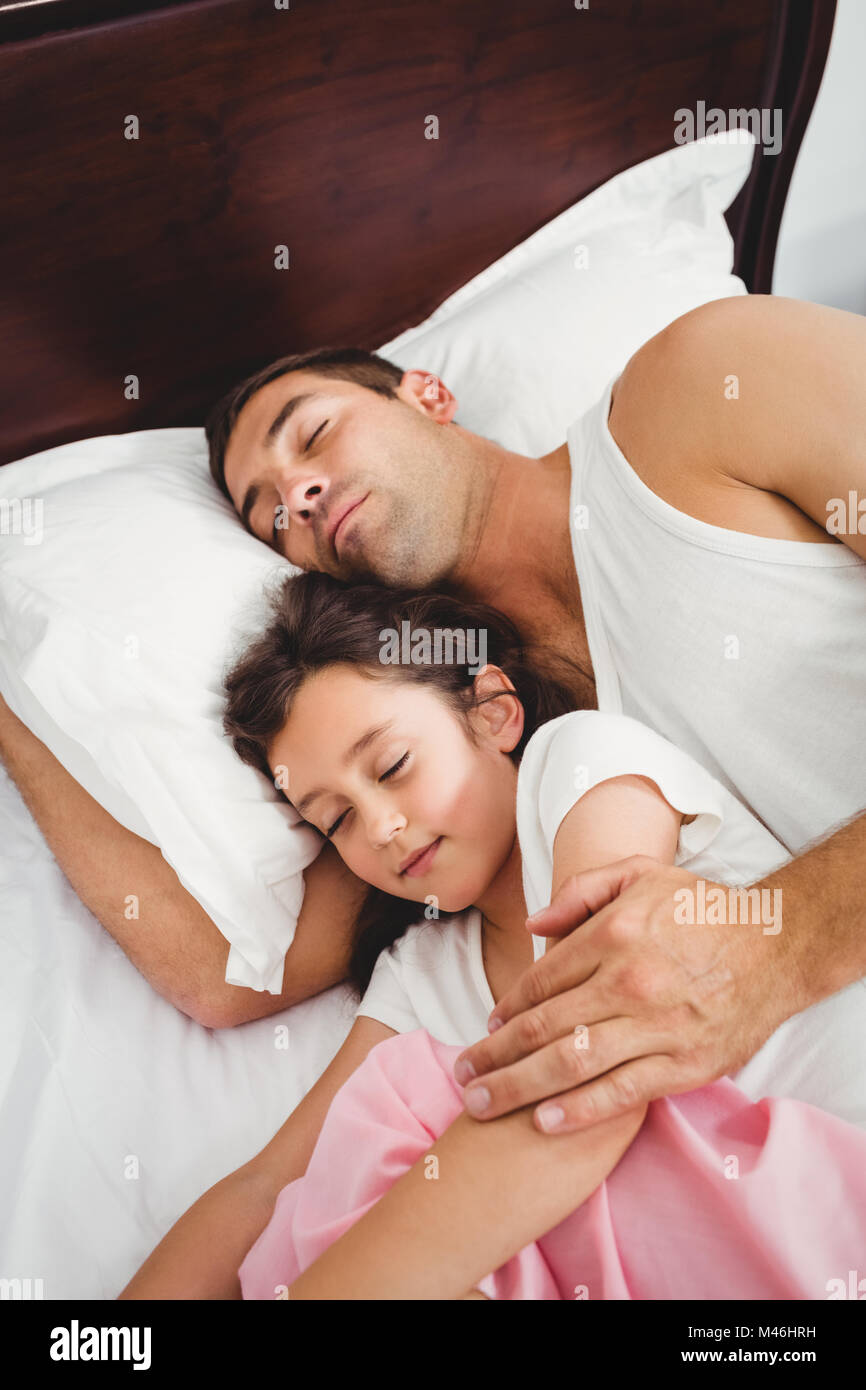 Daughter sleeping beside father on bed at home Stock Photo - Alamy