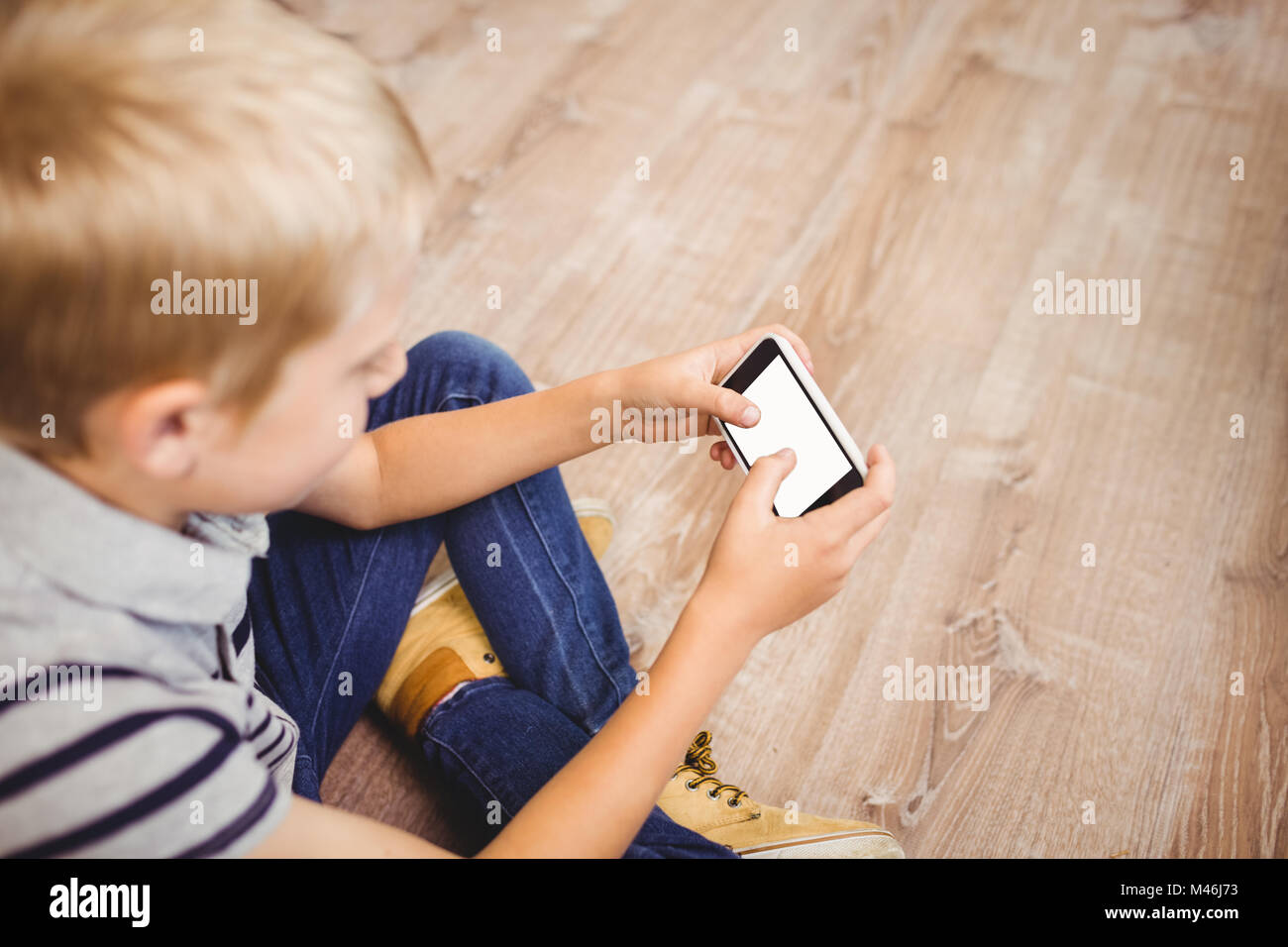 Boy using mobile phone while sitting on hardwood floor Stock Photo - Alamy