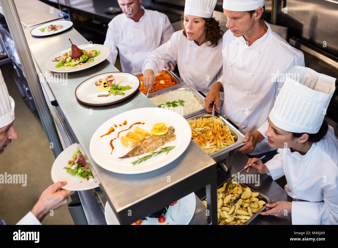Chefs handing dinner plates through order station Stock Photo - Alamy