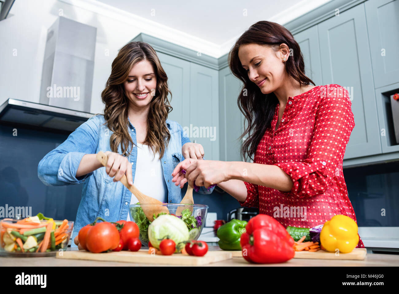Smiling female friends preparing vegetable salad Stock Photo - Alamy