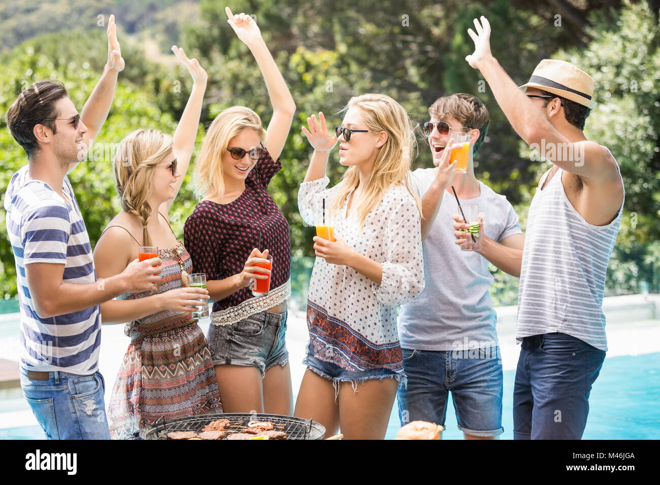 Group of friends raising their hands near pool Stock Photo - Alamy