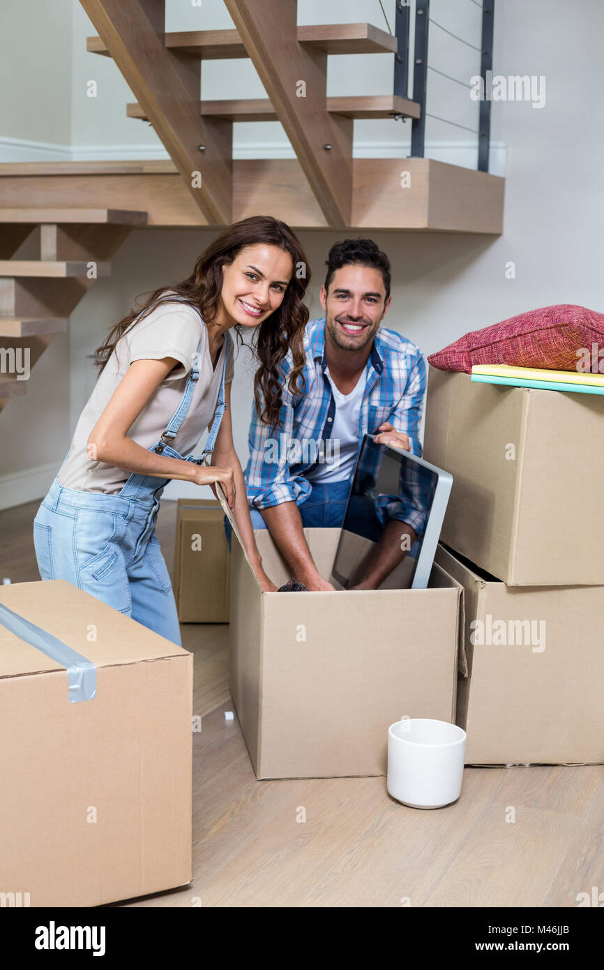 Portrait of smiling couple unpacking computer from cardboard box Stock ...