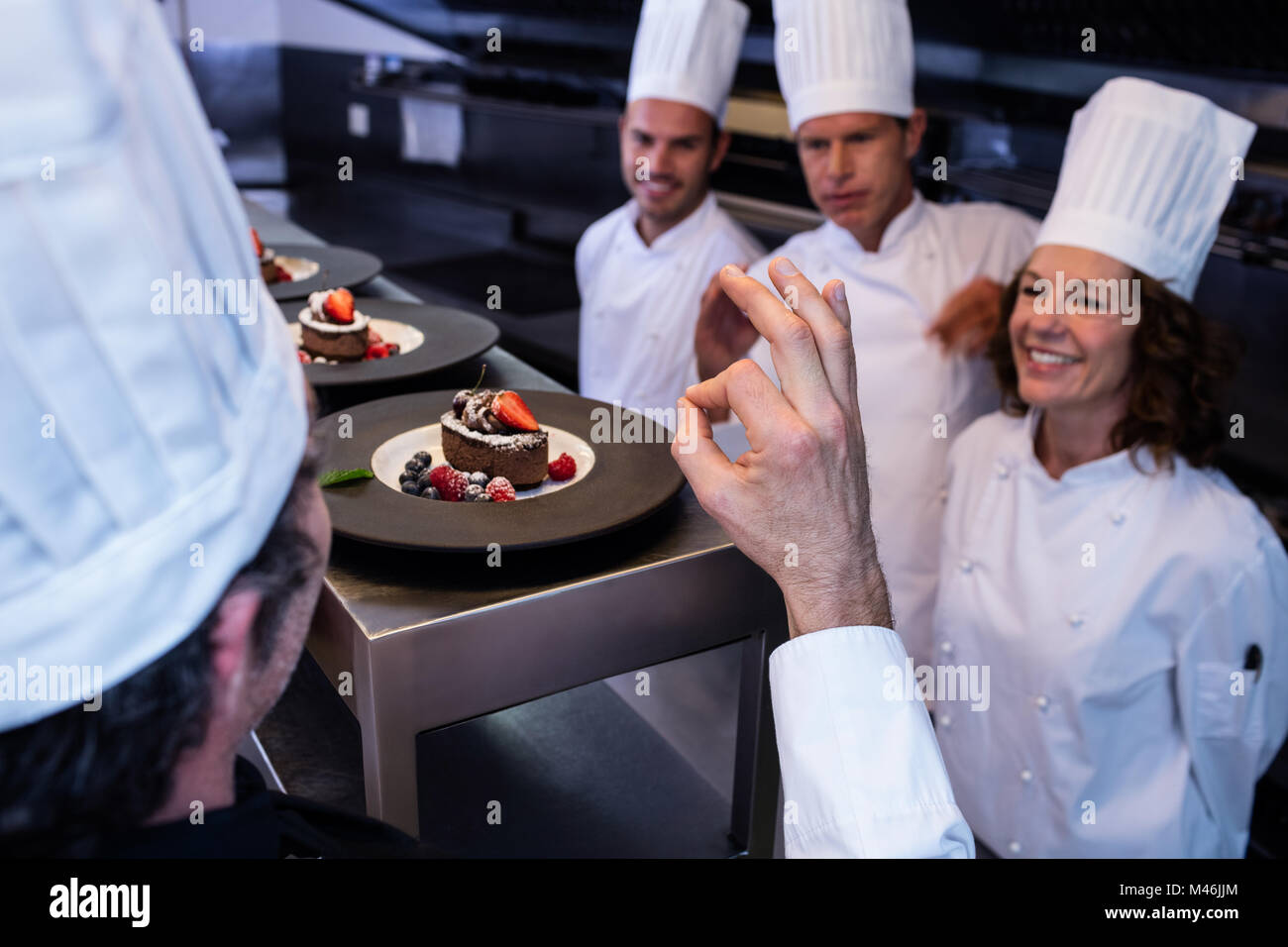Head chef showing ok hand sign after inspecting dessert plates Stock ...
