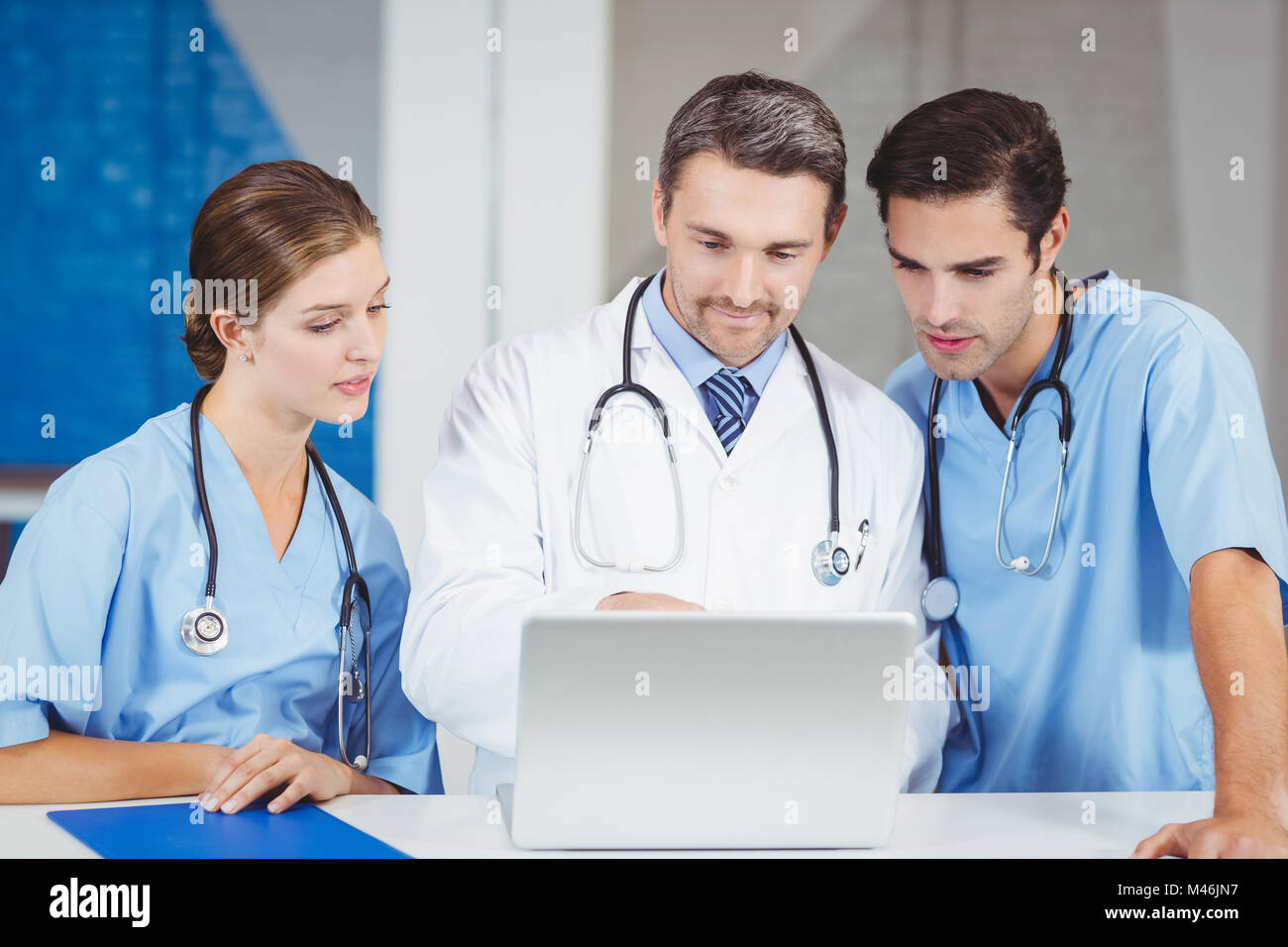 Concentrated doctors using laptop while standing at desk Stock Photo ...