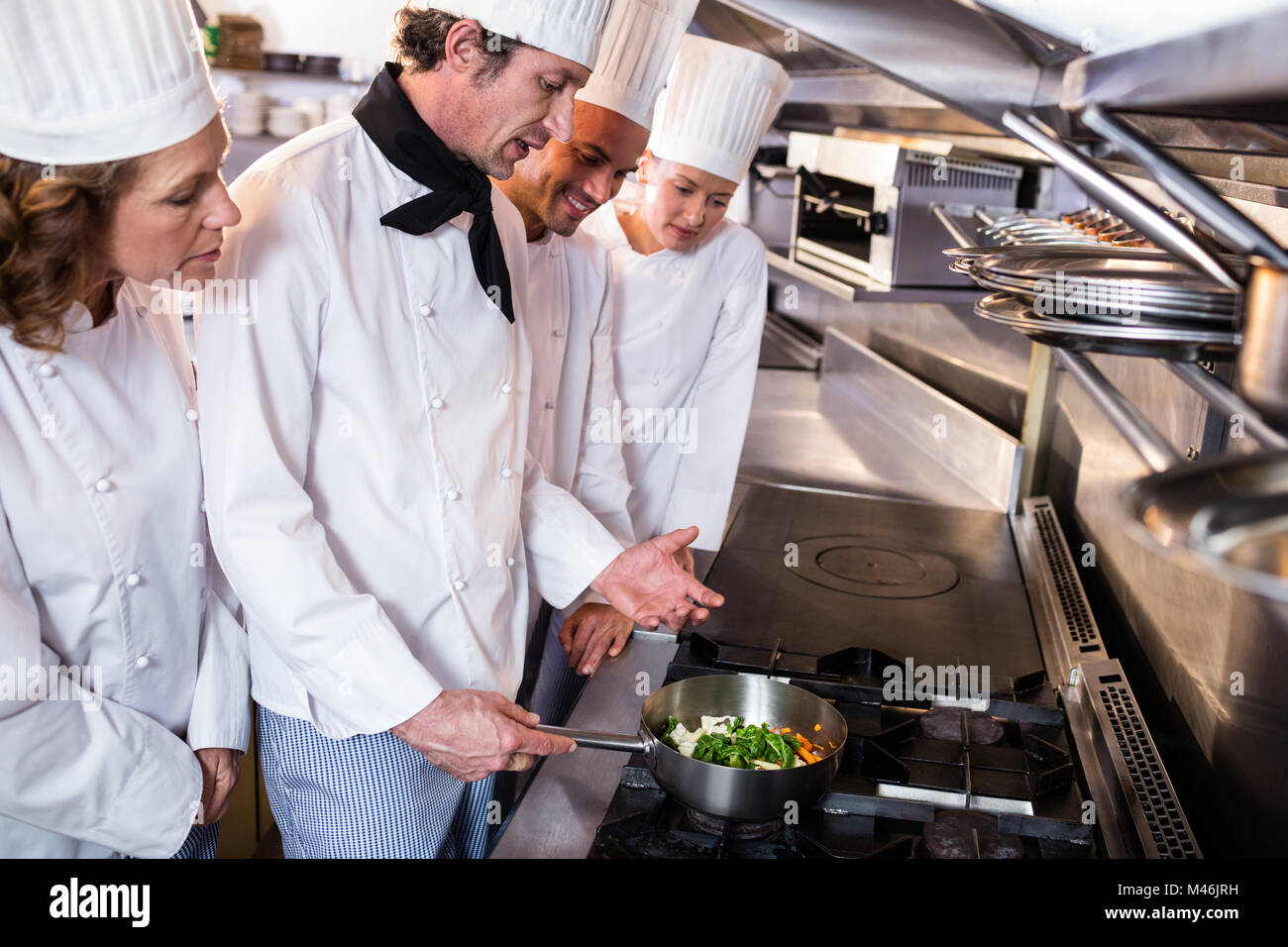 Experienced head chef explaining to his colleagues in the kitchen Stock ...