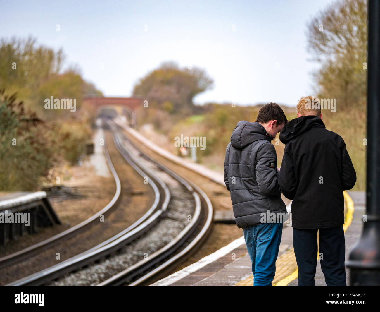 Two boys wait for local commuter train, at Charing train station, Kent ...
