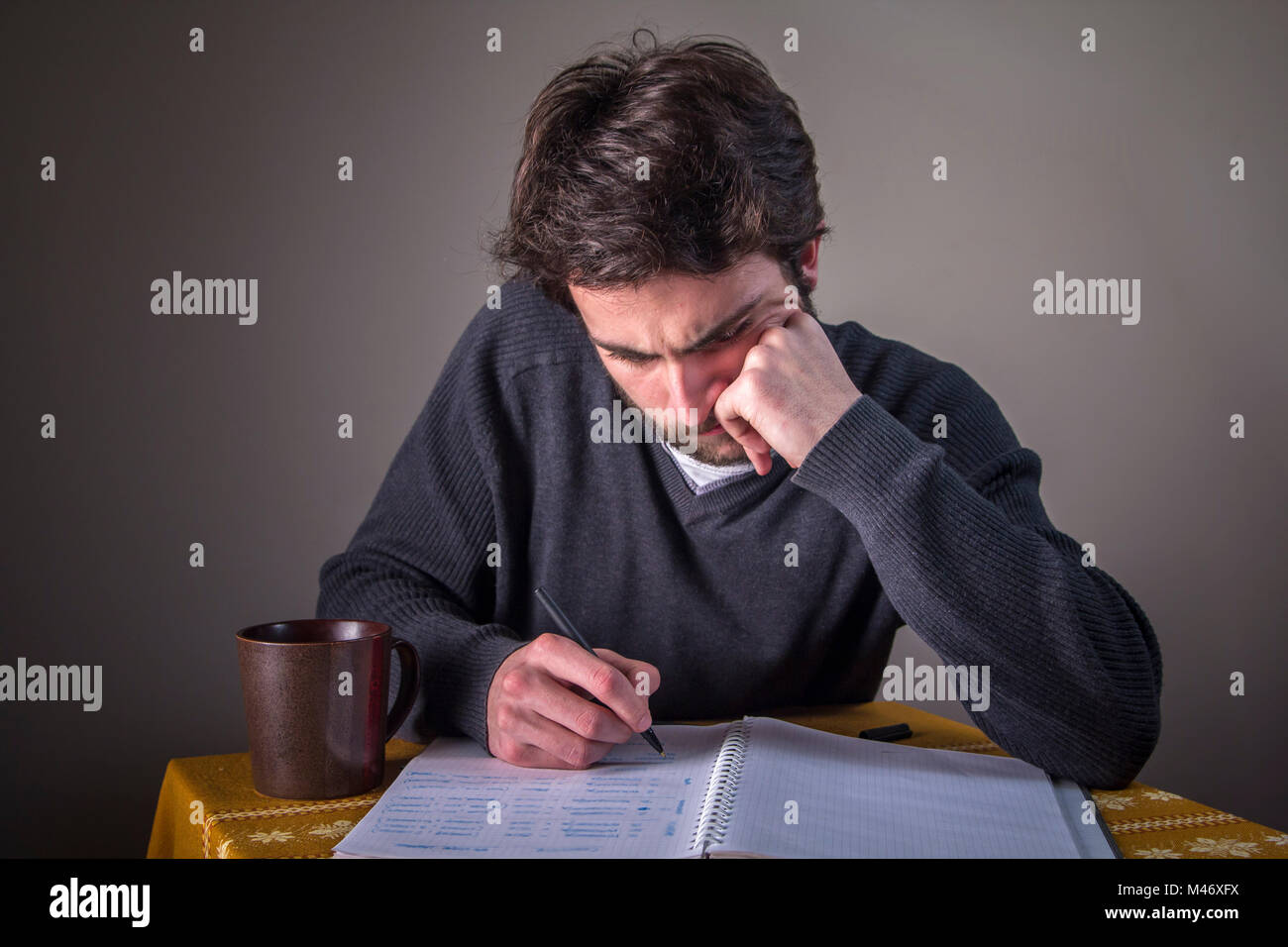 Young man calculating, writing down and studying Stock Photo - Alamy