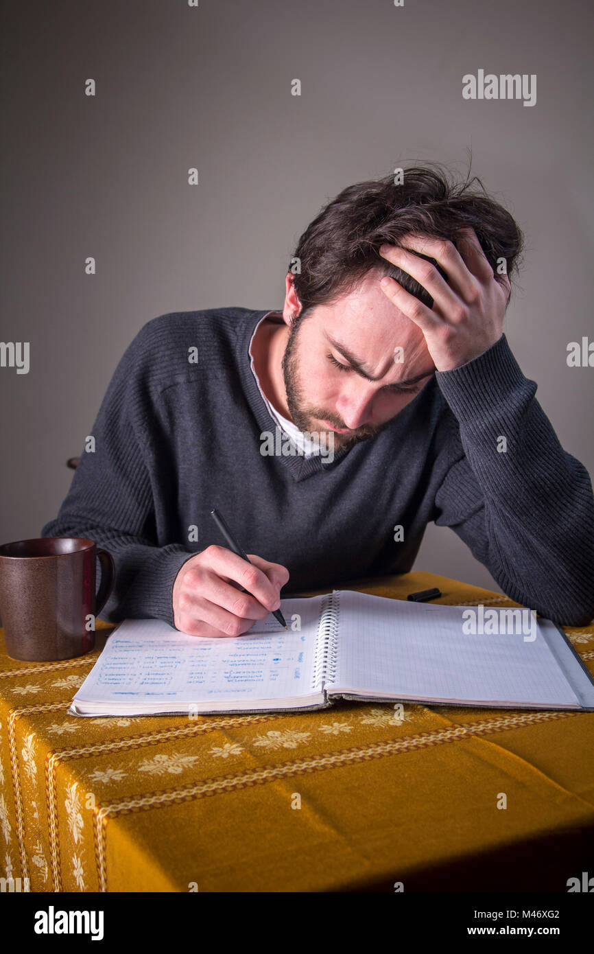 Young man calculating, writing down and studying Stock Photo - Alamy