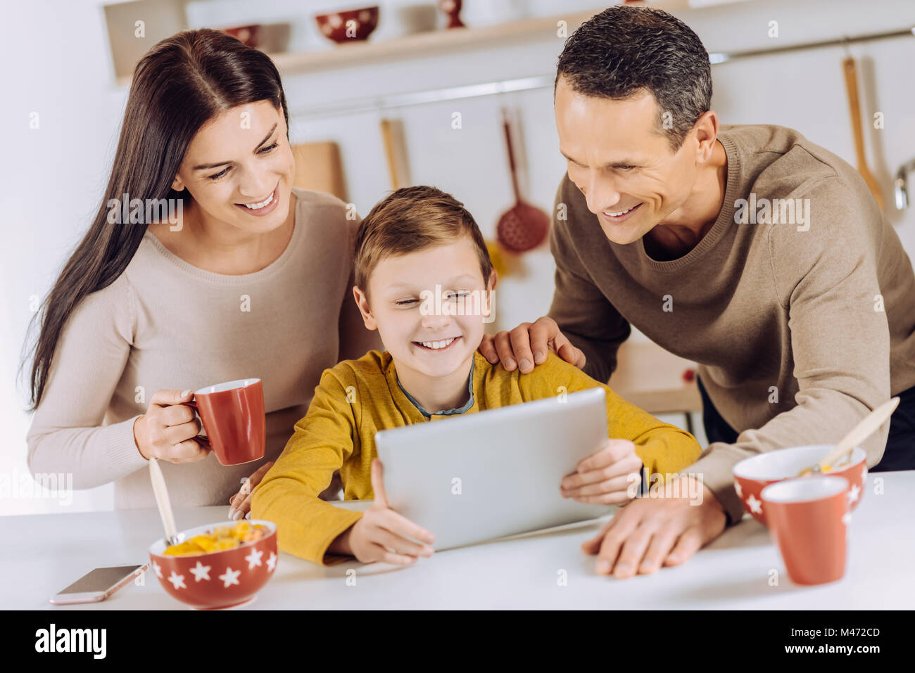 Cheerful parents watching a video together with his son Stock Photo - Alamy