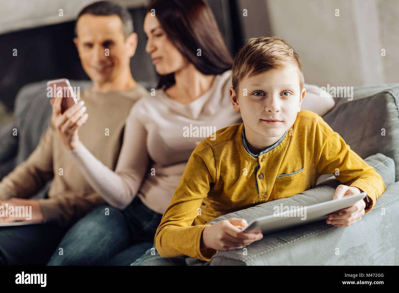 Lovely boy posing while playing on tablet Stock Photo - Alamy