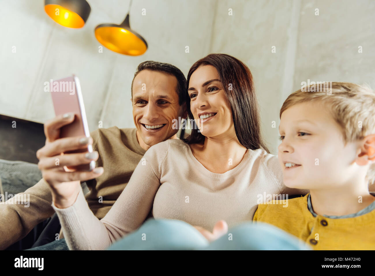 Happy family reading from mothers phone together Stock Photo - Alamy