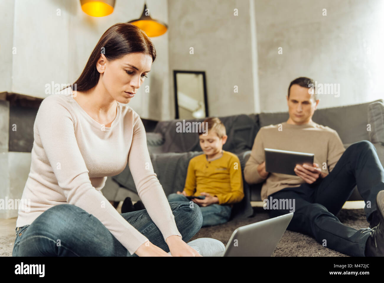 Young woman working on laptop away from her family Stock Photo - Alamy