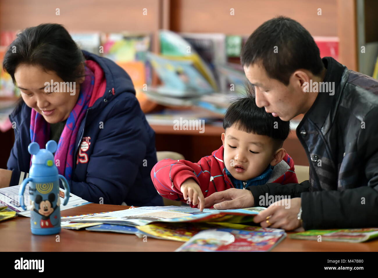Taiyuan. 15th Feb, 2018. A kid reads a book with parents in the Shanxi ...