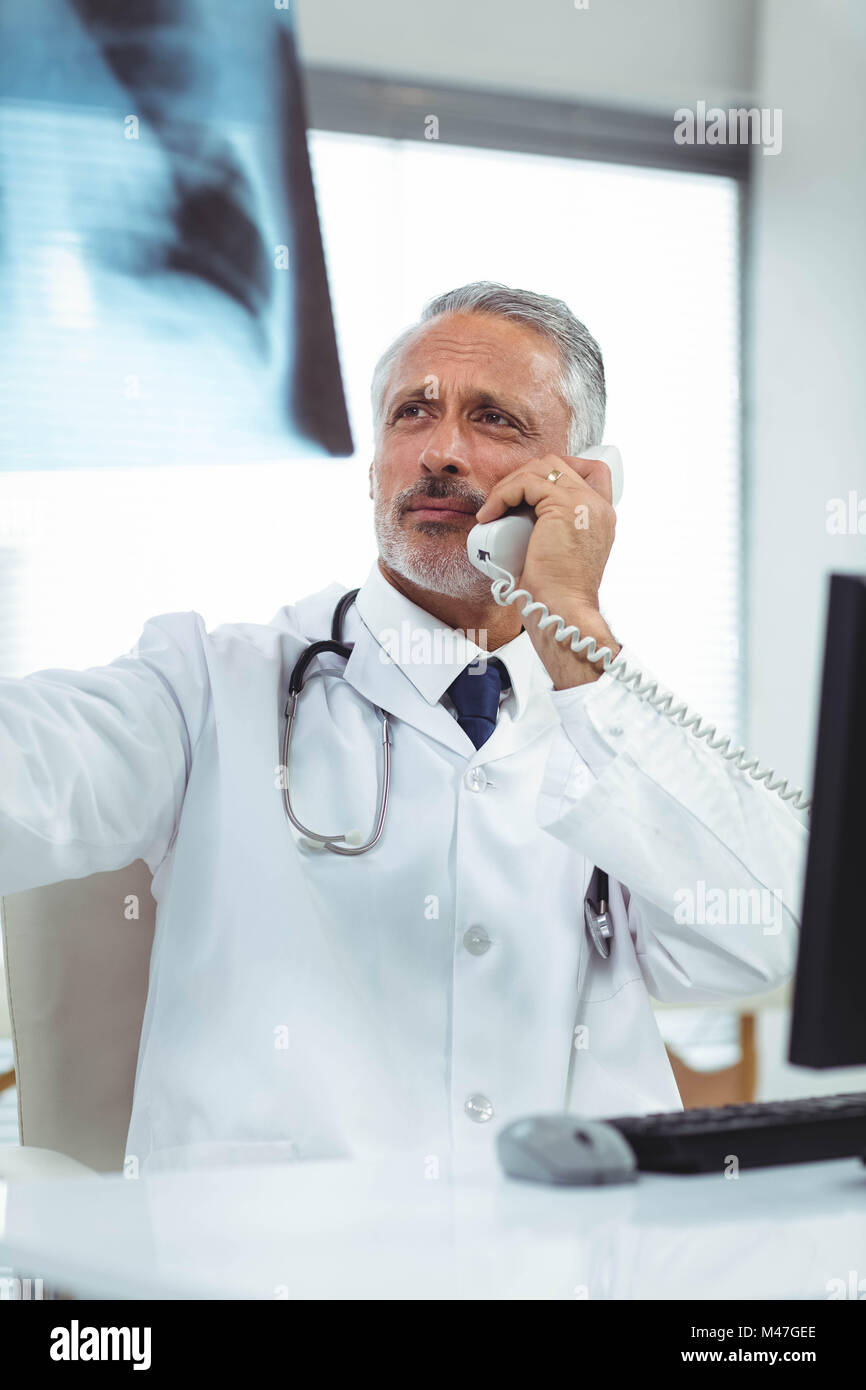 Doctor checking a x-ray report while talking on phone Stock Photo - Alamy