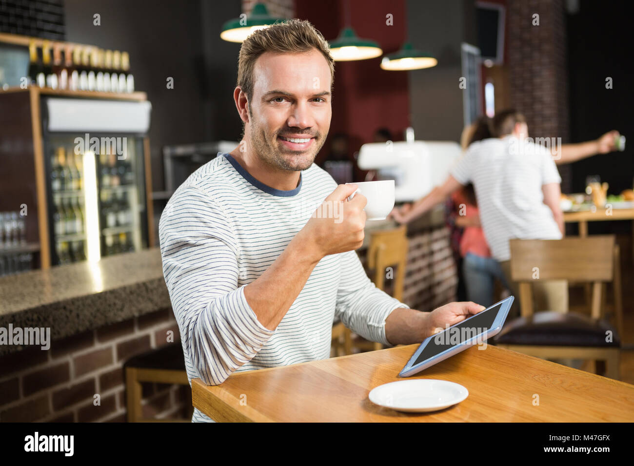 Handsome man using tablet computer and having a coffee Stock Photo - Alamy